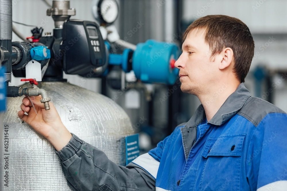 An inspector in overalls checks the condition of the water purification ...