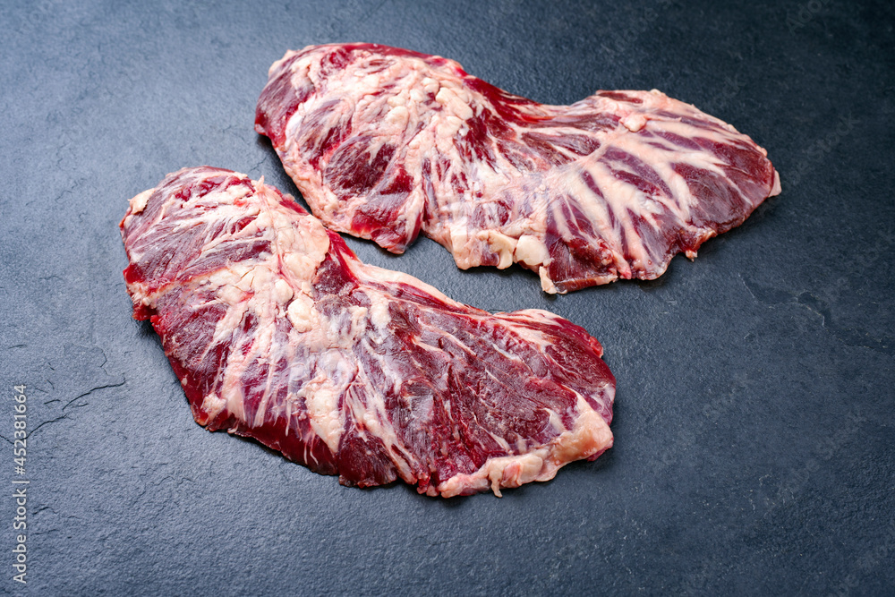 Raw wagyu spider beef steak offered as top view on a black board with ...