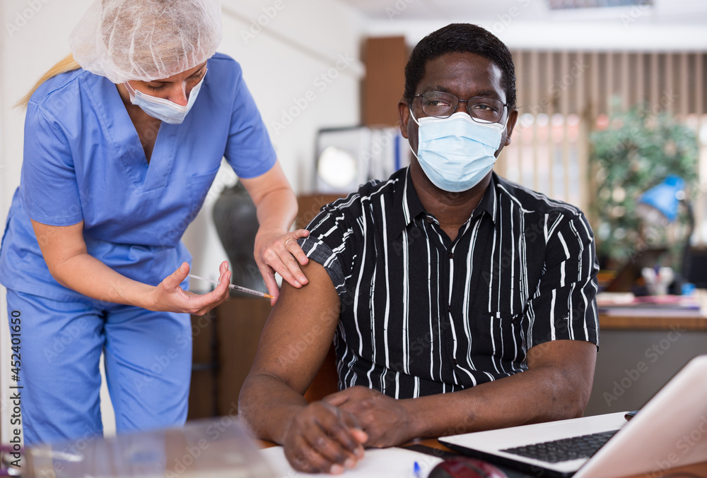 African american office employee in protective face mask getting ...