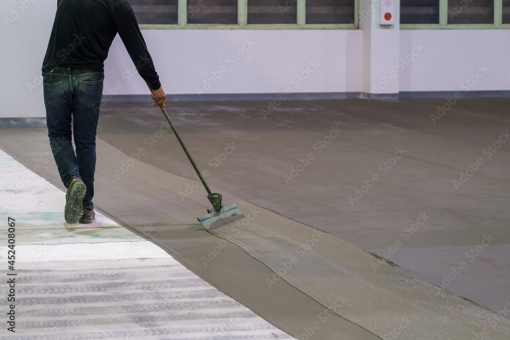 Construction worker using trowel spreading moisture blocking epoxy ...