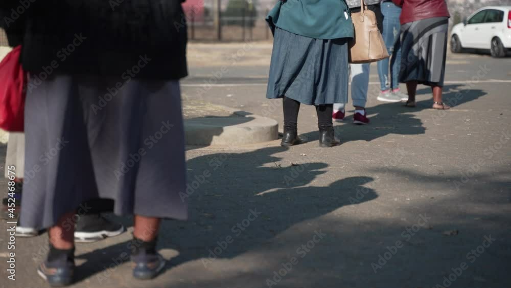Elderly African women stand in a long queue waiting outdoors, their ...