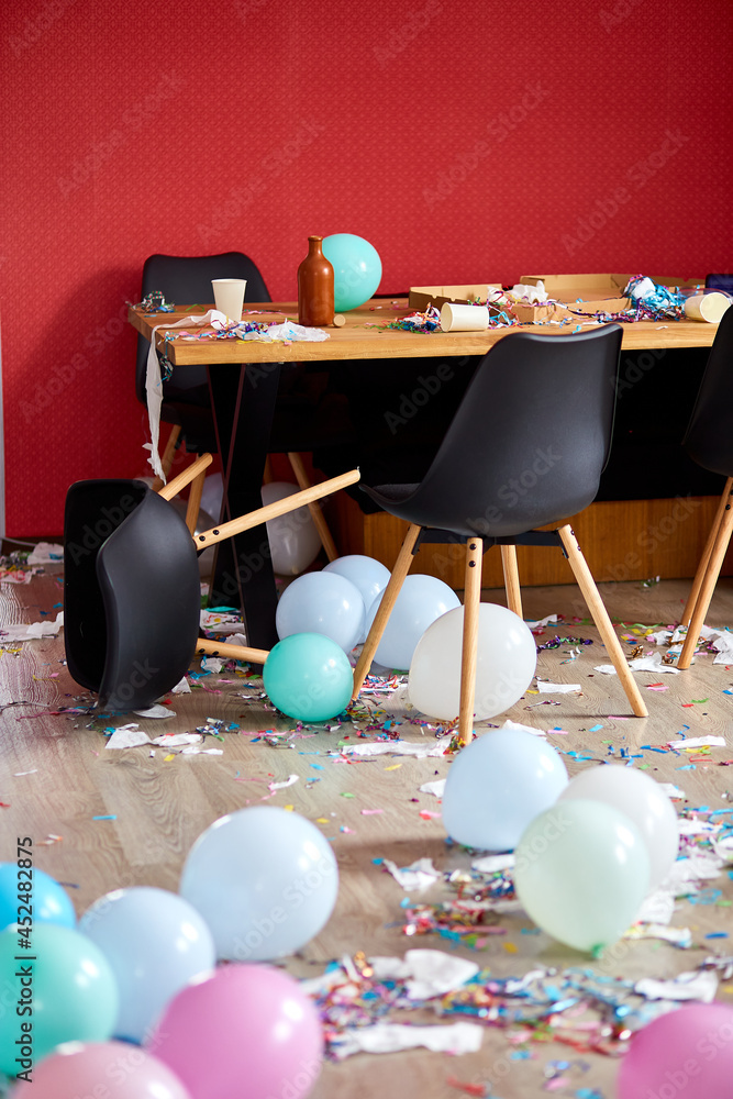 After party chaos, messy in livving room at home, table with pizza and ...