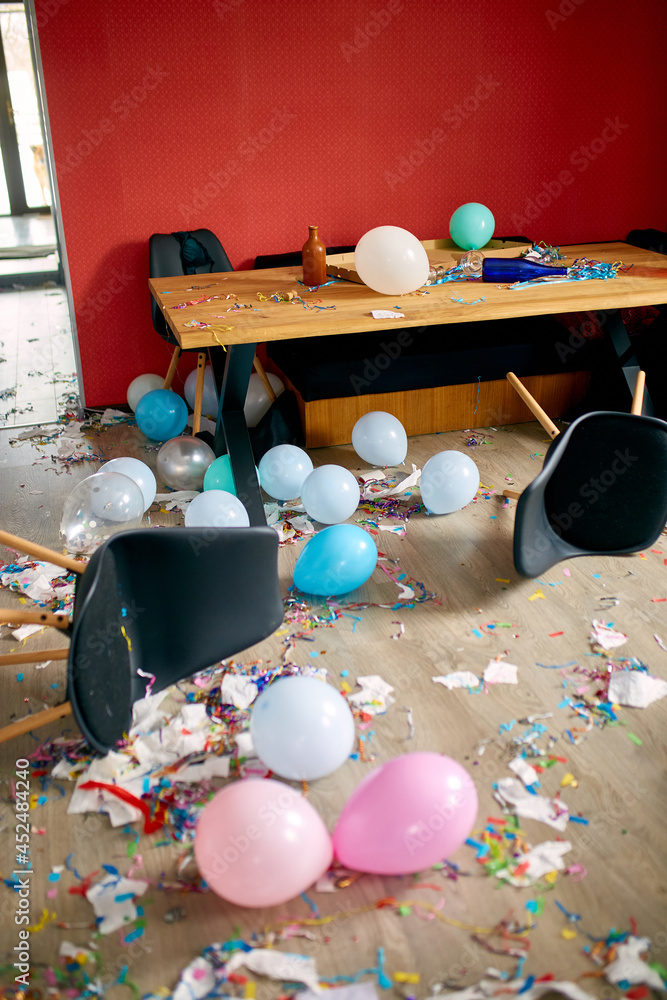 After party chaos, messy in livving room at home, table with pizza and ...