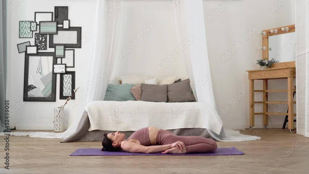 Slender, flexible, caucasian middle-aged woman with black hair in beige ...