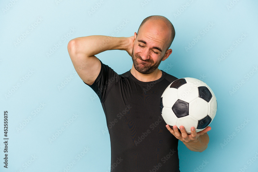 Young business bald man playing football isolated on blue background ...