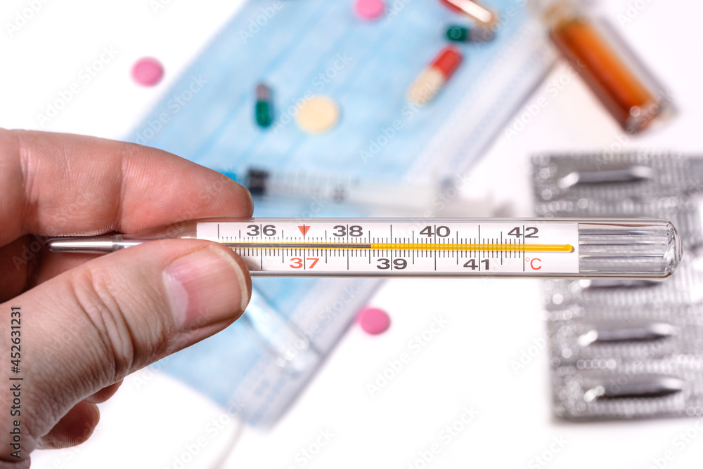 The hand holds a thermometer with a high temperature indicator against ...