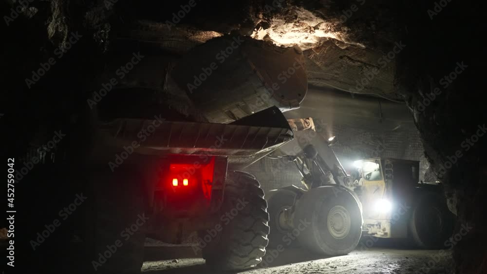 Underground loader loads ore mass into an underground dump truck Stock ...