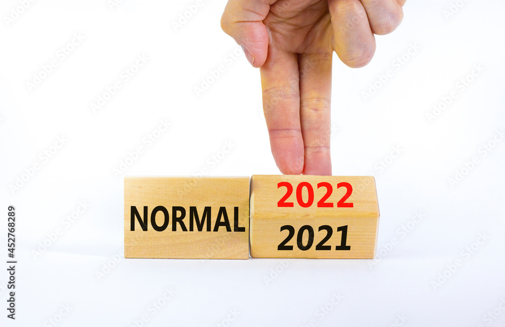 Symbol of covid-19 normal in 2022. Doctor turns a wooden cube and ...
