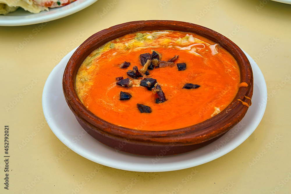 A "tapa" of salmorejo served in an earthenware dish with a few slices ...