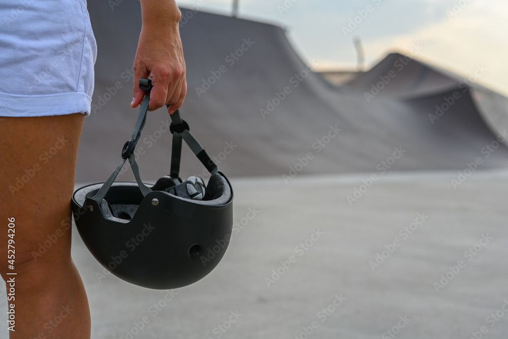 A woman holds a safety helmet after riding in an extreme park. The ...