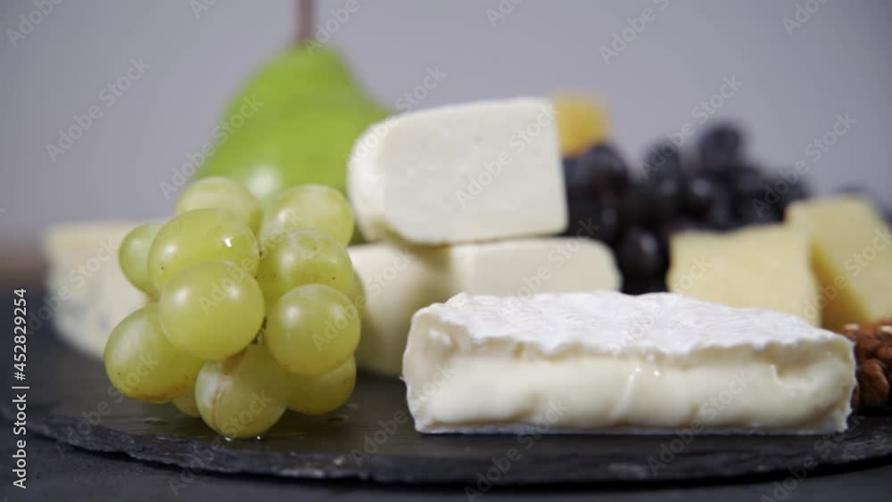 Vidéo Stock A cheese plate with various fruits rotates on its axis ...