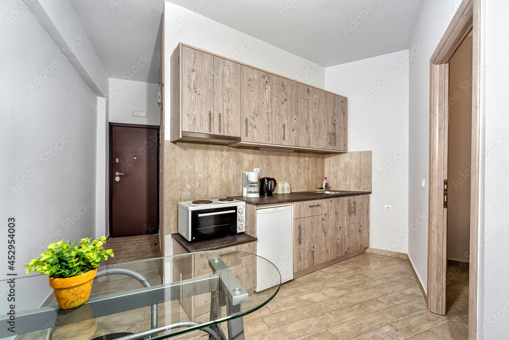 Beige color kitchenette and glass dining table. Equipped with mini ...