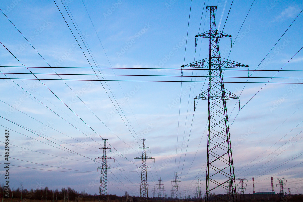 High voltage power lines in the middle of a field at sunset ...