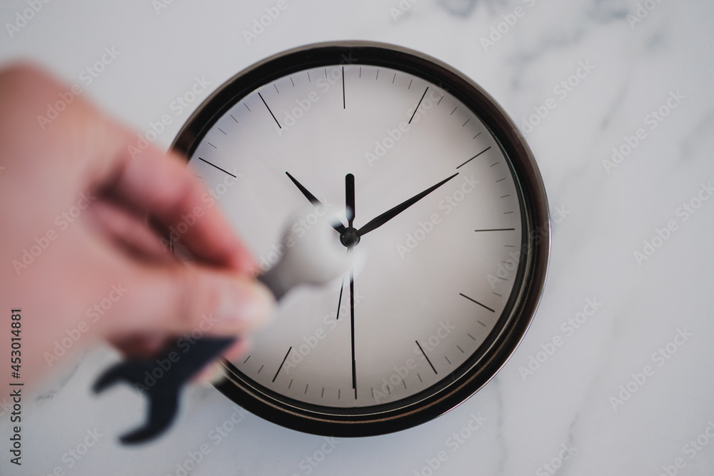 hand holding wrench in front of big clock, metaphor of productivity and ...