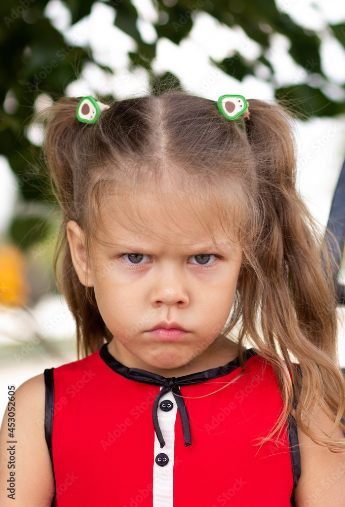 Angry caucasian little girl of five years old with gloomy face looking ...