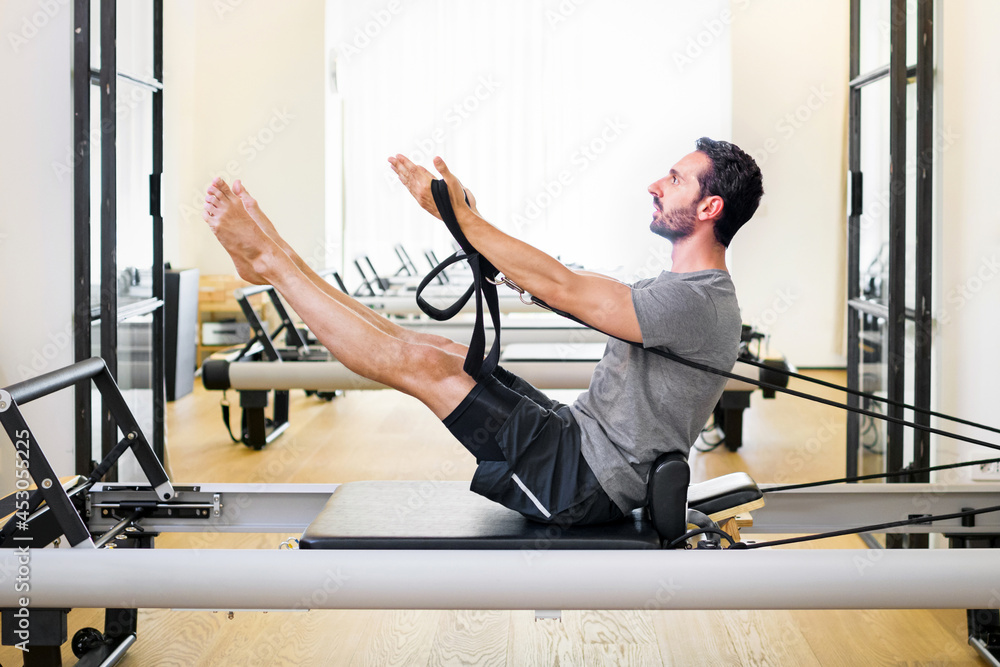 Fit muscular man doing a teaser pilates exercise on a reformer Stock ...
