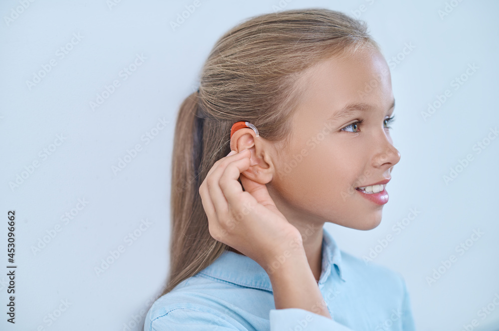 Profile of girl touching ear with hearing aid Stock Photo | Adobe Stock