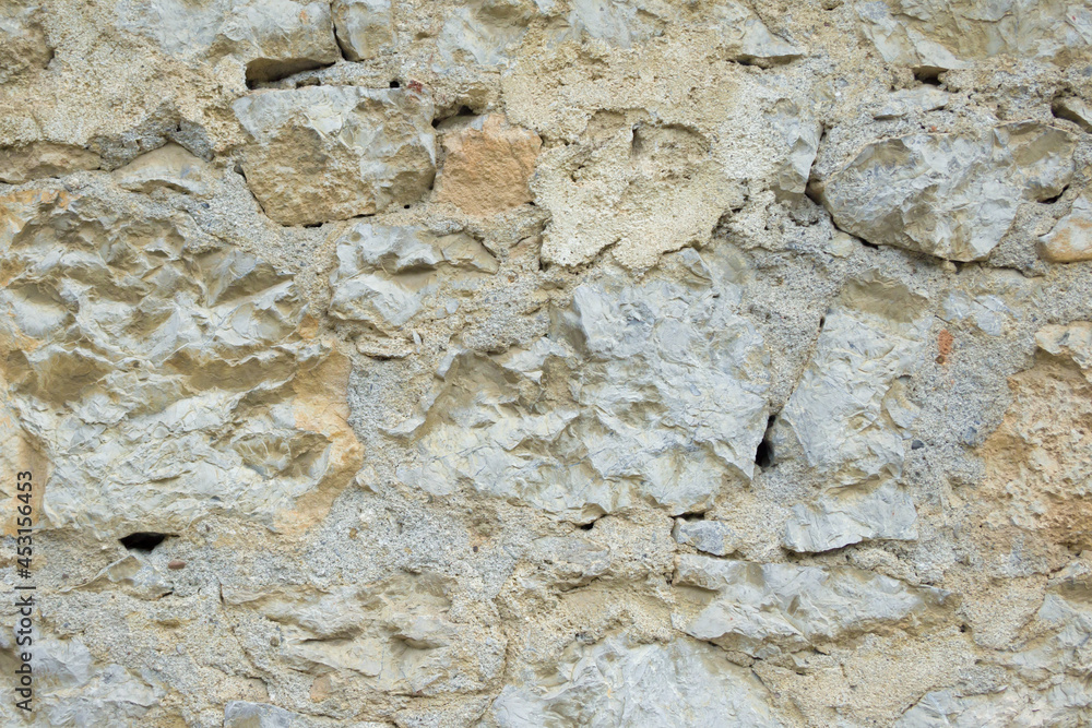 Frontal view of a wall made of brown-yellow rough rough stones of ...