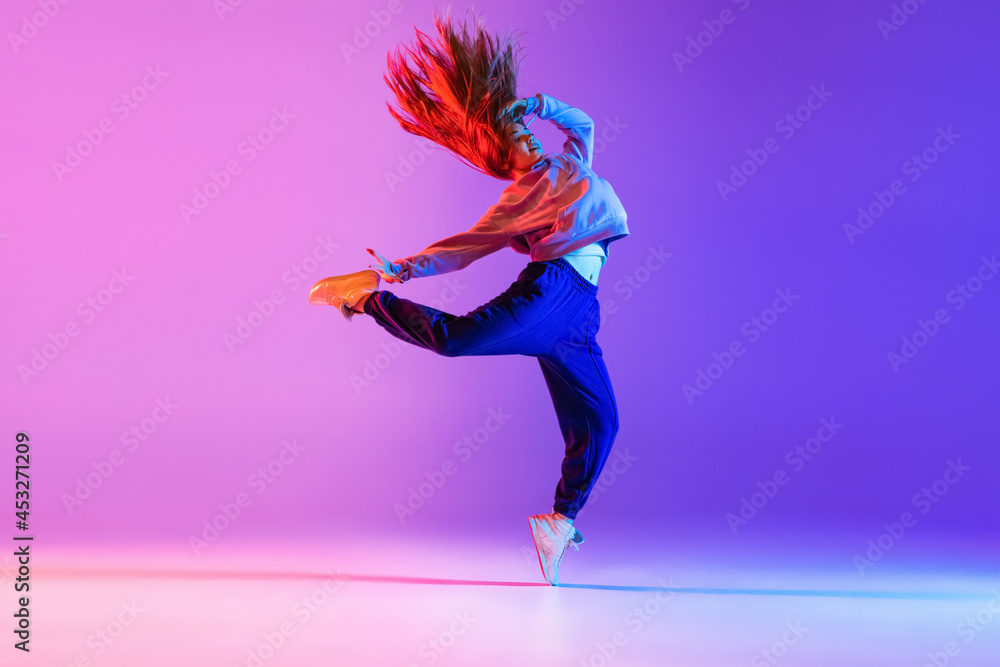 Young stylish girl dancing hip-hop isolated on gradient pink purple ...