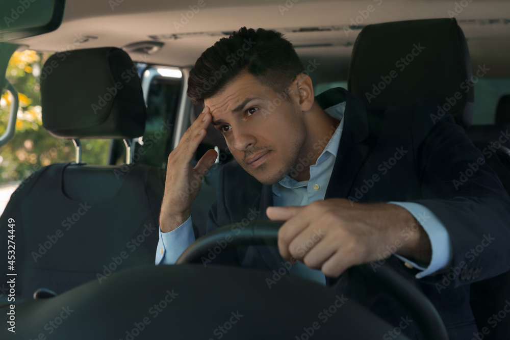 Stressed man in driver's seat of modern car, view through windshield ...