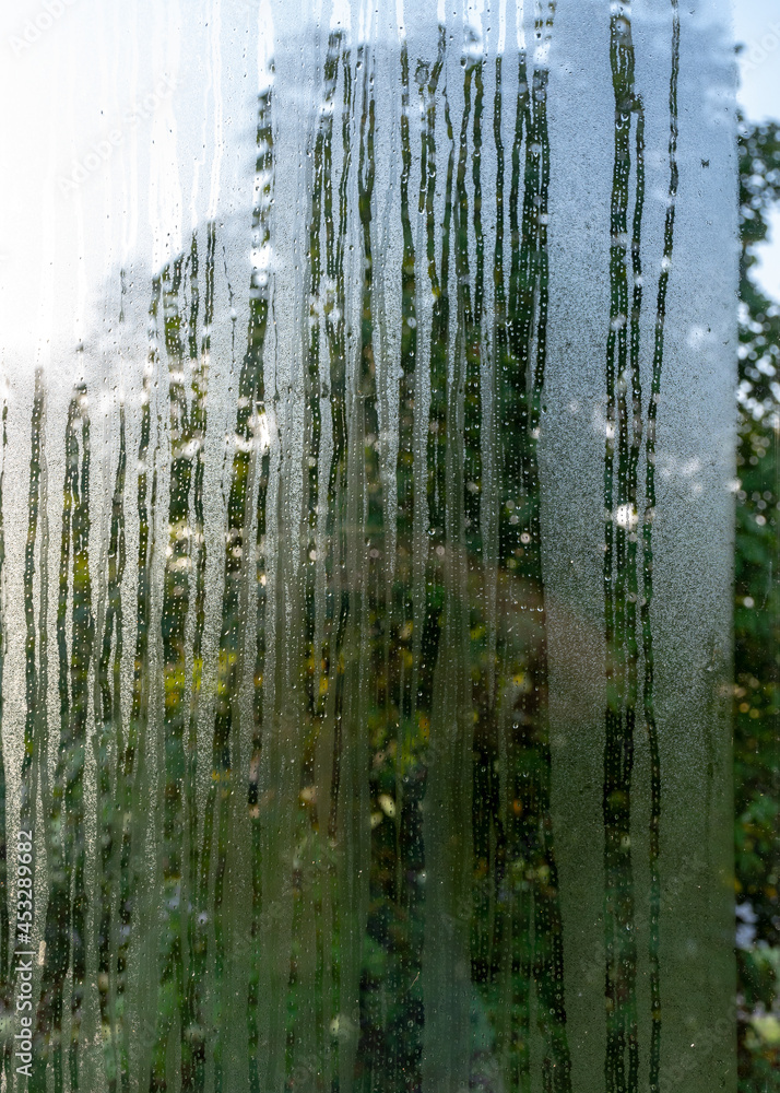 photography with wet and sweaty window, raindrop texture, blurred tree ...