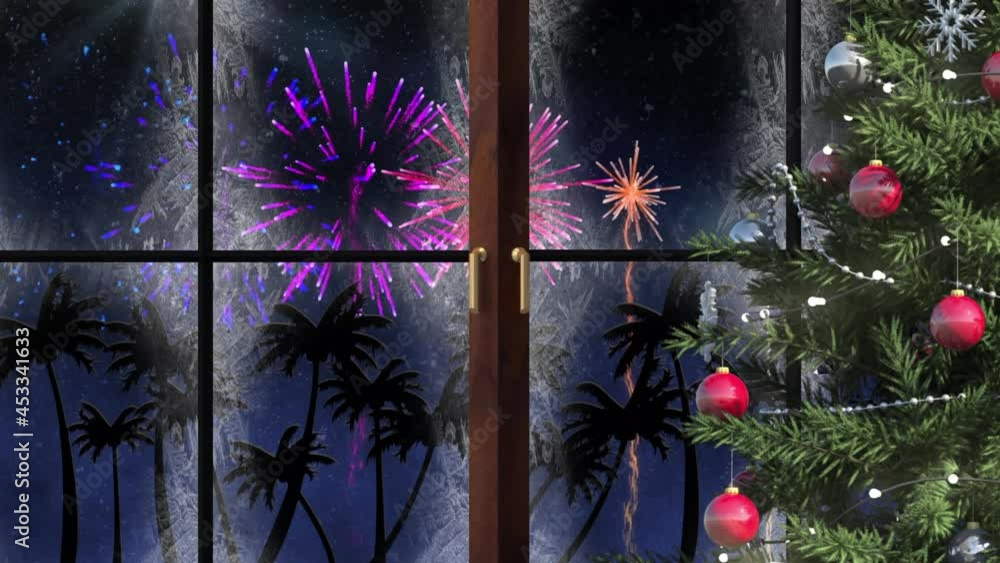 Christmas tree and wooden window frame against palm trees and fireworks ...
