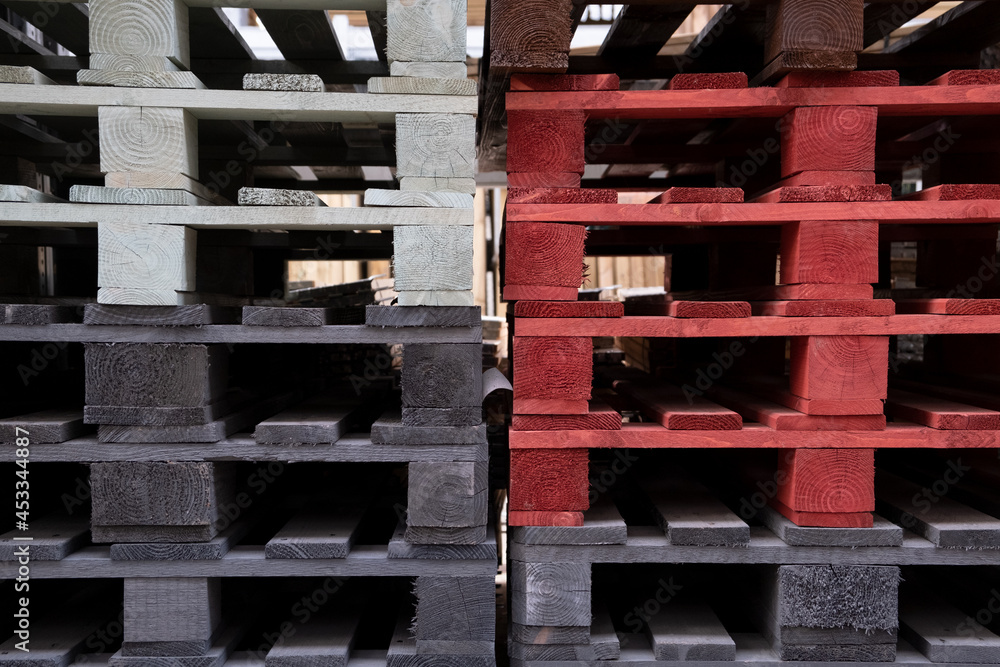 Different colors of wooden pallets are stacked in a row at hardware ...