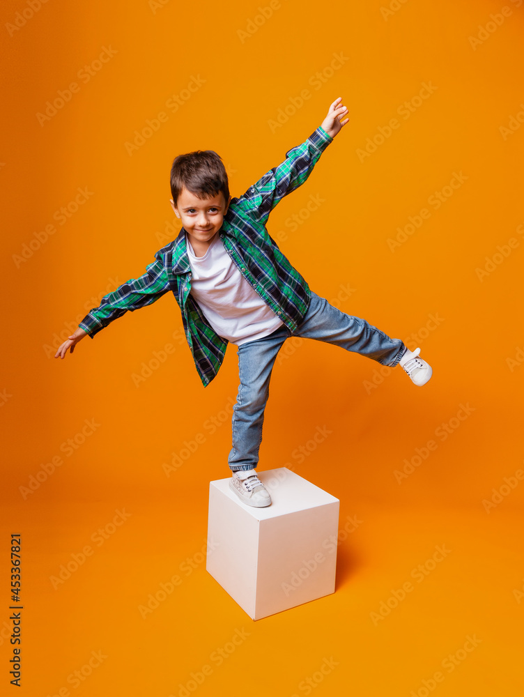 happy little boy smiling and holding balance, standing on one leg on a ...