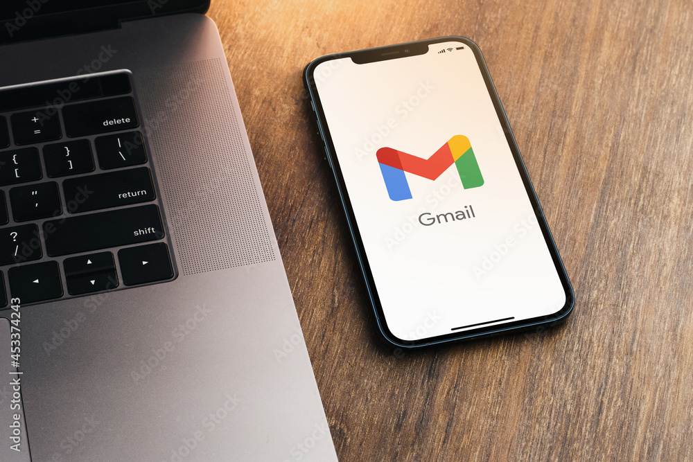 Gmail app on the smartphone screen on wooden background with a computer ...