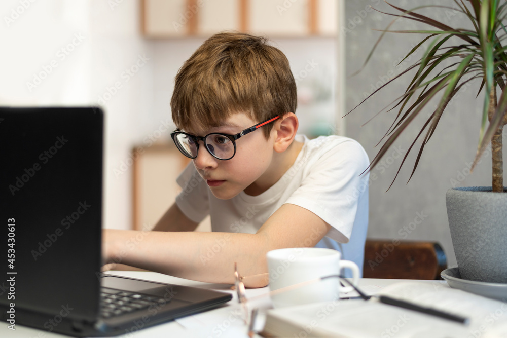 Teenage boy is engaged in programming. Child with glasses stares ...