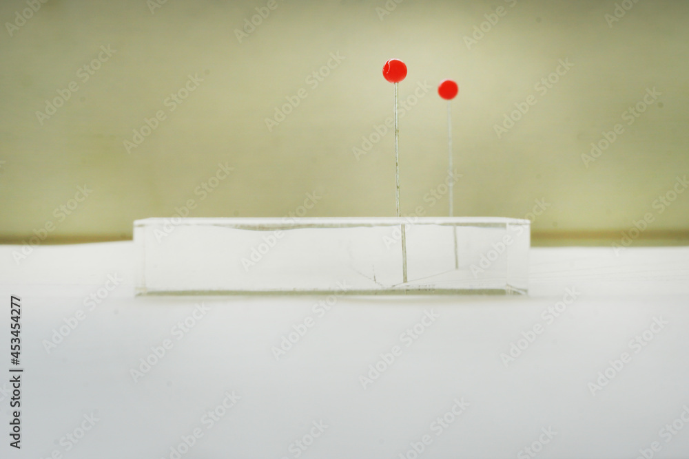 Pins are placed in front of and behind a square glass rod to study the ...