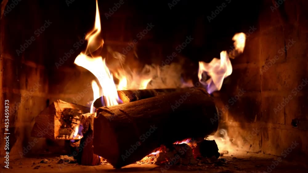 Wooden logs in fire on brick fireplace background. Wood burning in fire ...
