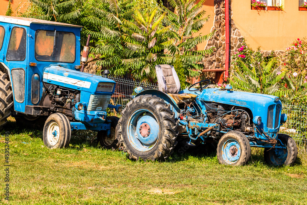 Old blue vintage tractor in fron of farm land in Viscri Village ...