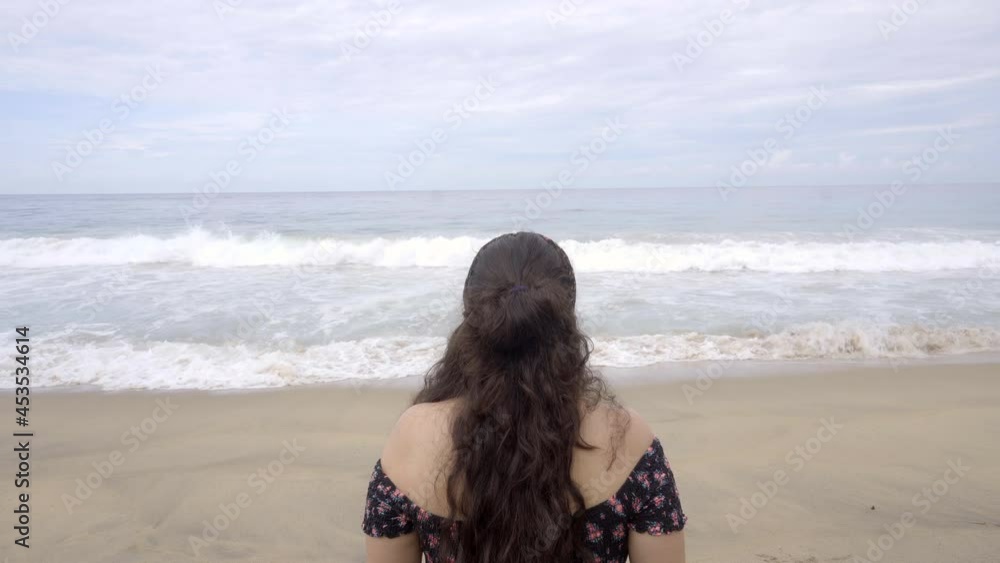 Mujer latina de espaldas contemplando el mar en la playa en Pie de la ...