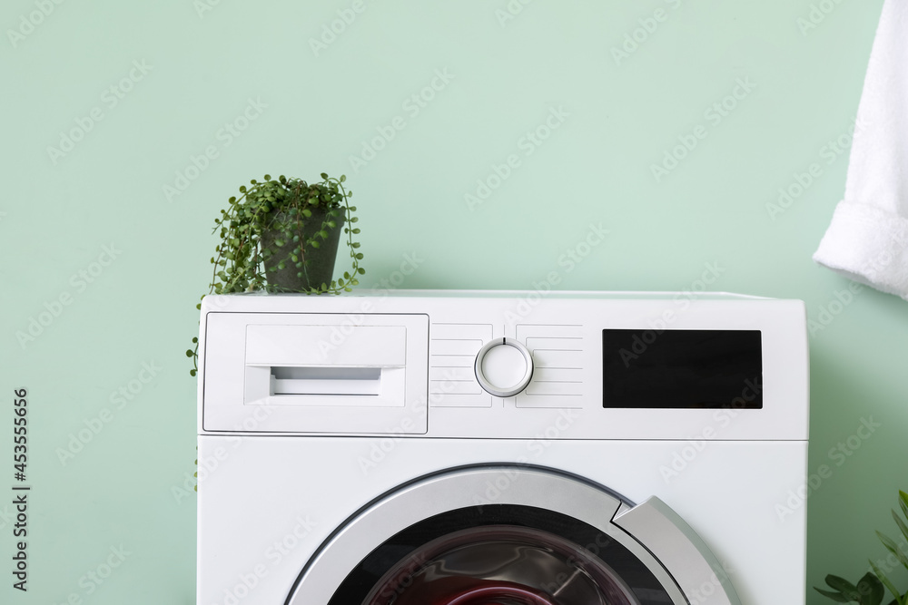 Modern washing machine with houseplant near color wall Stock Photo ...