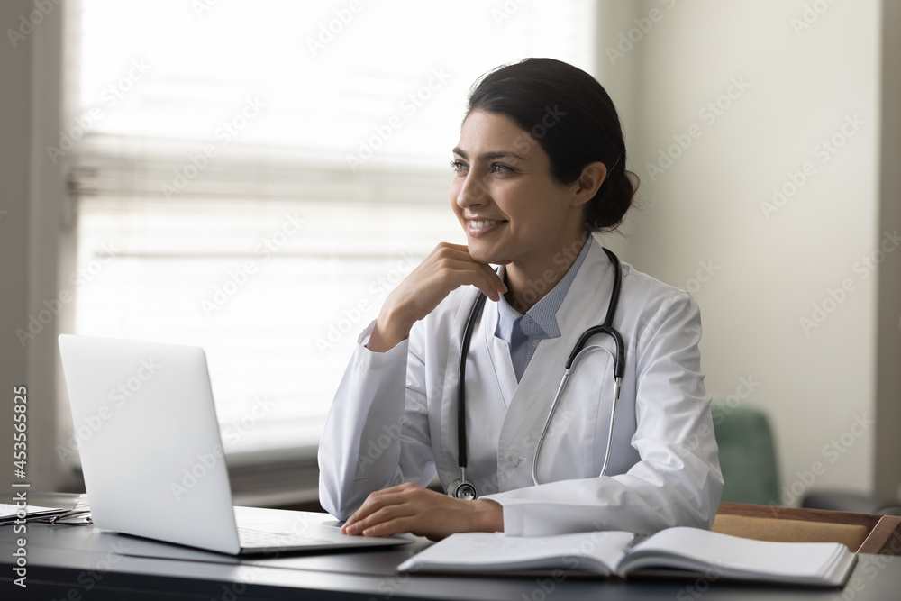 Happy motivated young indian therapist gp doctor looking in distance ...