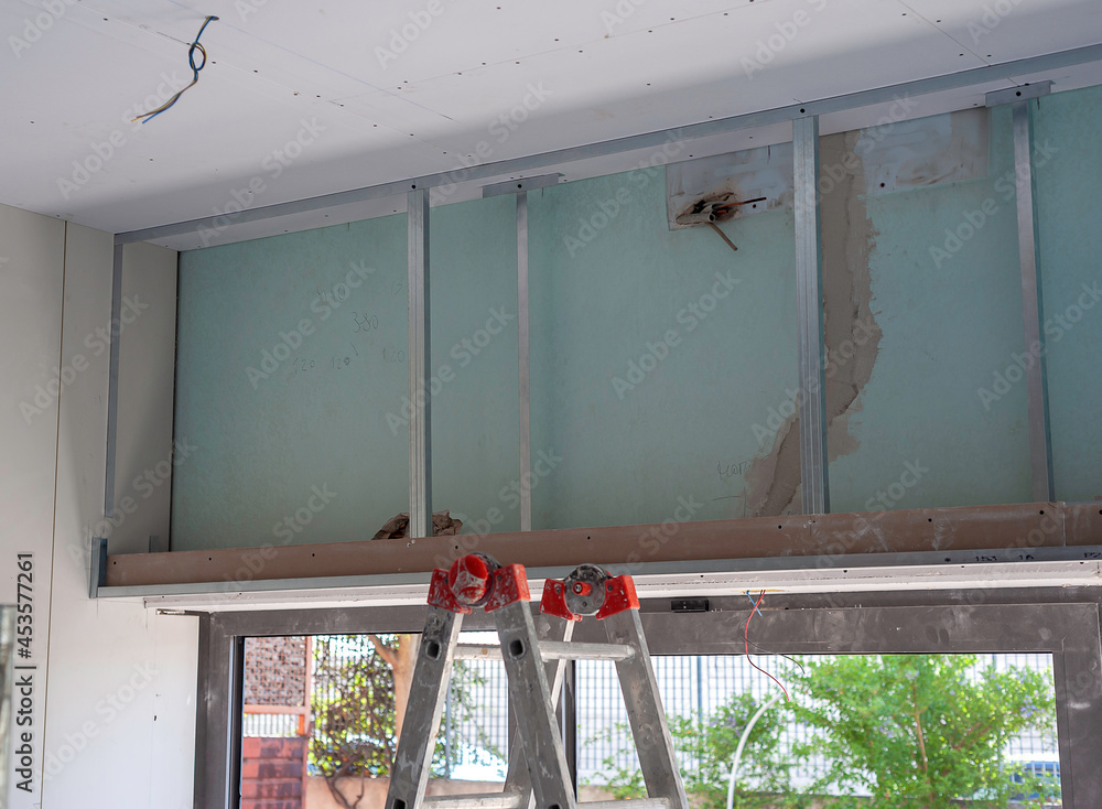Construction worker assemble a suspended ceiling with drywall and ...