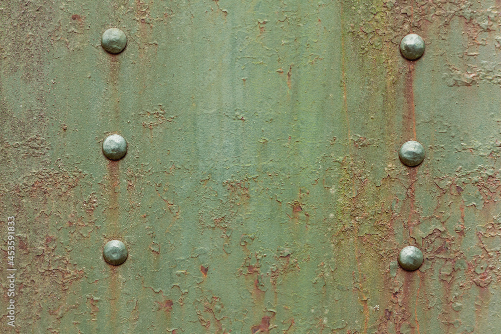 Surface of a sheet of armored metal with rivets and faded green ...