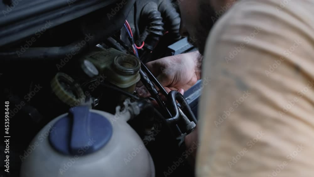 Man unscrews part in car using his hands and wrench. Replacement of ...