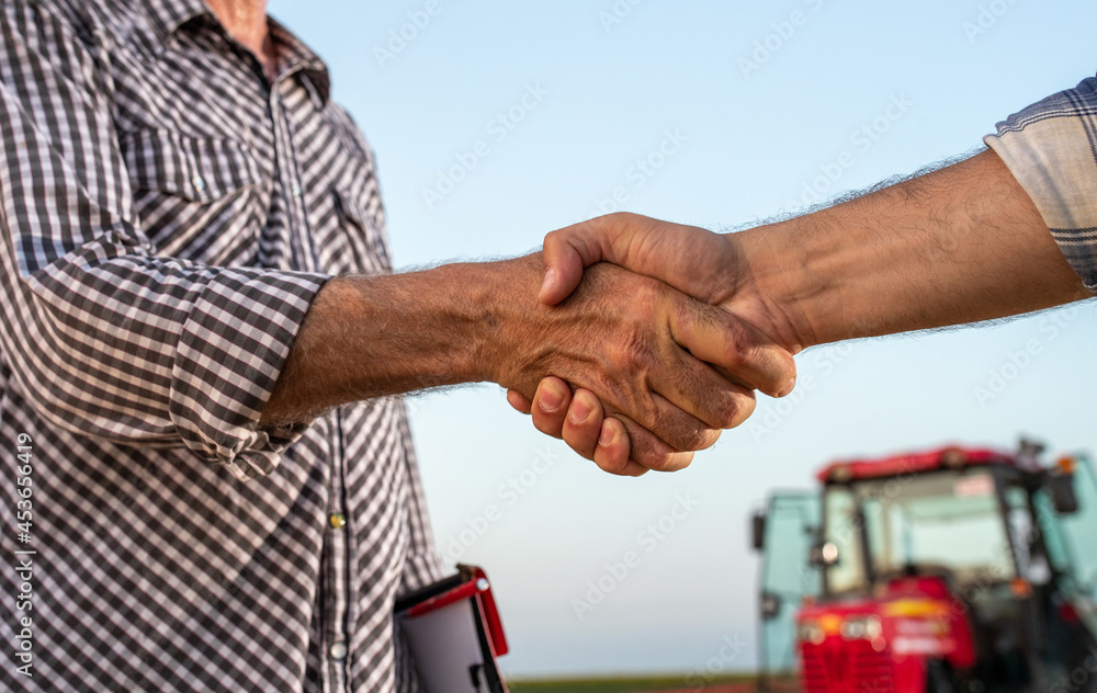 Two farmers shaking hands in field during harvest Stock Photo | Adobe Stock