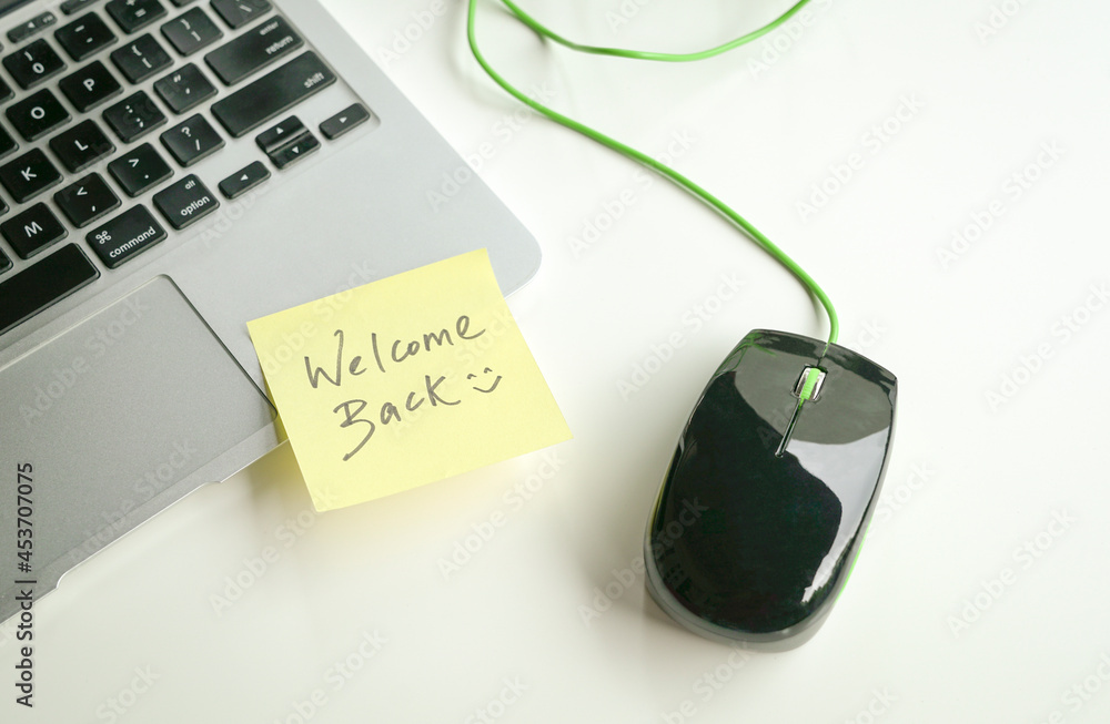 Welcome back with smiley written on yellow paper stick on keyboard next ...