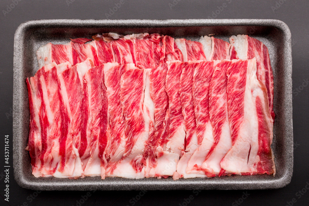 Sliced raw beef place in a row on a black plastic tray isolated on a ...