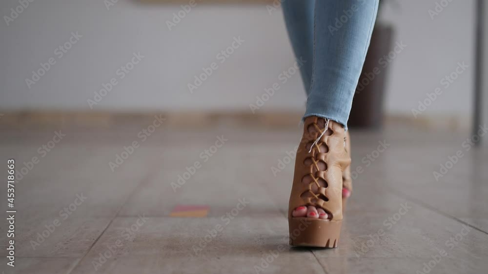 Close up of woman's feet walking towards camera in high heels and jeans ...