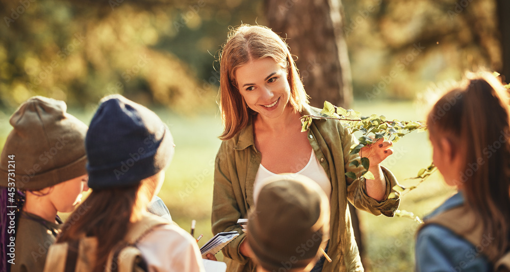 Children listening to teacher and looking at green leaf while having ...