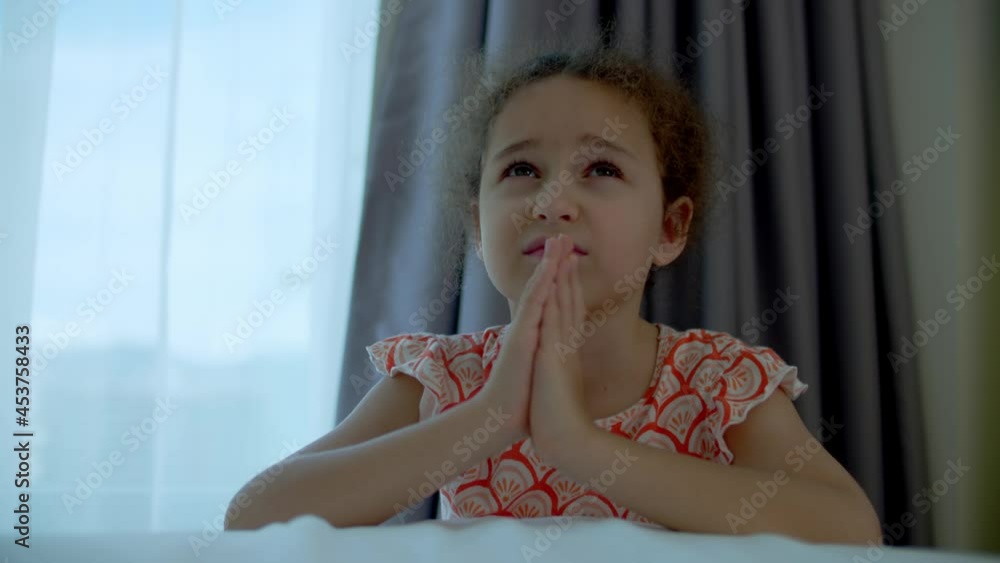 Little girl is praying in her room.Close up portrait of child concept ...