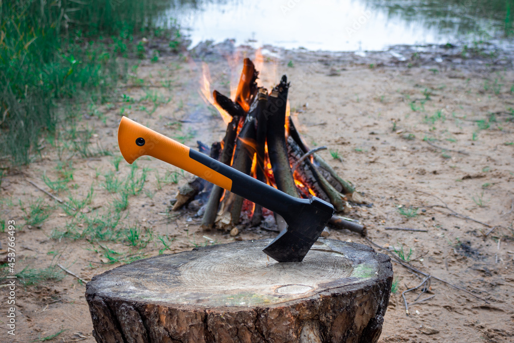 Fotka „The axe is stuck in a log. Chopping wood for a fire on the ...