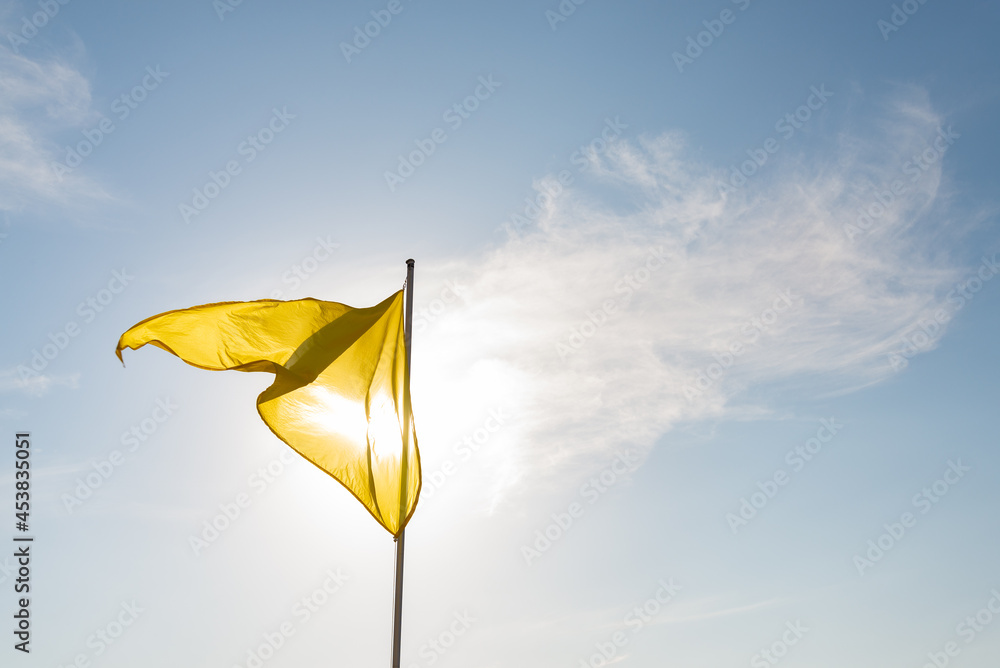 Yellow flag flapping in the wind and shadowing the sun, San Sebastian ...