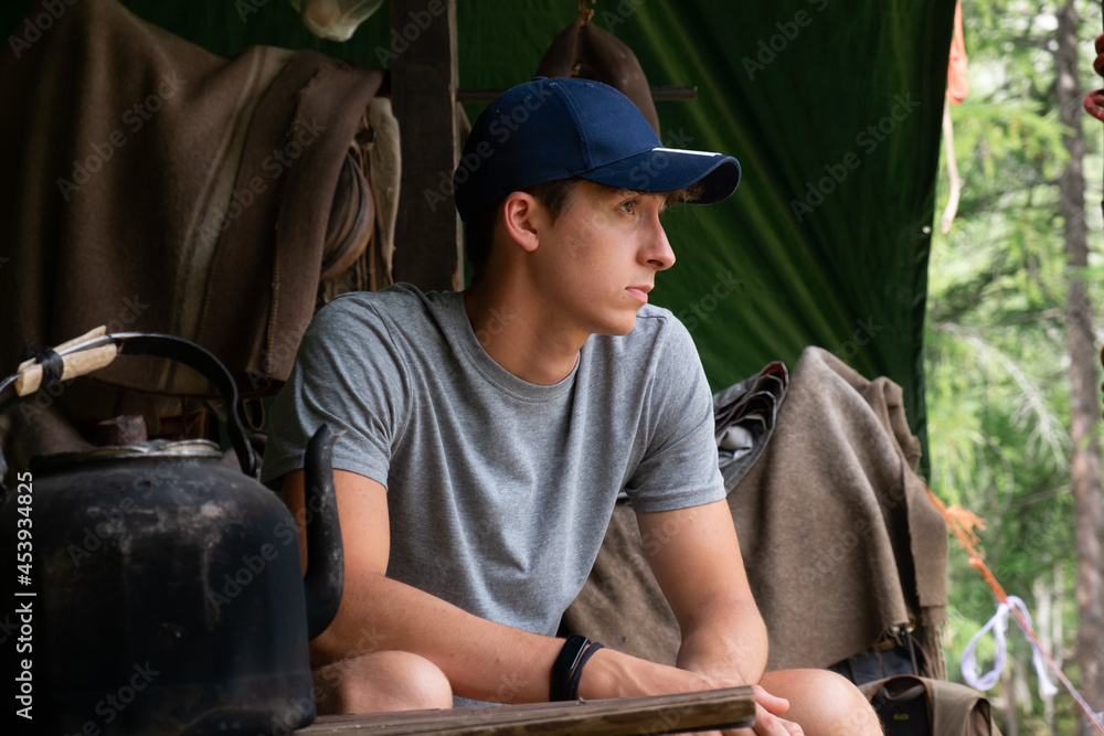 Camping boy with hat, outdoor living in the wilderness. Young man in ...