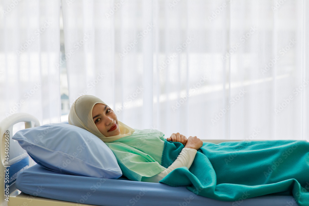 Portrait of sick young female Asian Muslim patient lying on hospital ...