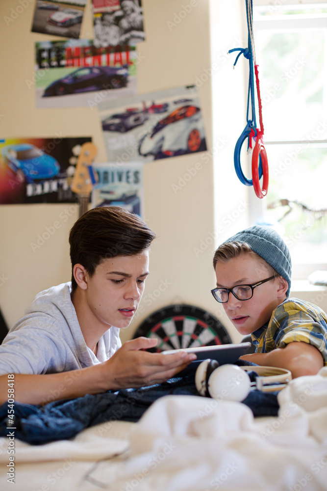 Two teenage boys using electronic devices in room Stock Photo | Adobe Stock